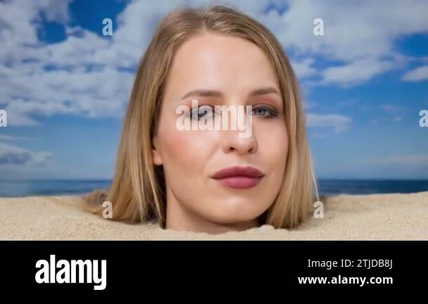 A pretty woman buried up to her head on a beach looking around her ...