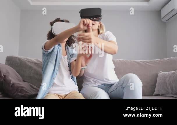 Mother and son wearing virtual reality headset vr glasses in living ...