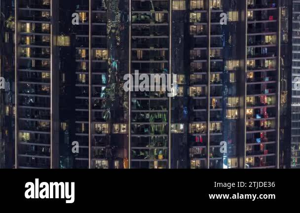 Illuminated panoramic windows in apartments of a high class building at ...