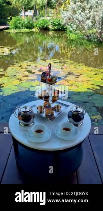Afternoon tea at a water pond, high tea in a tropical garden in ...
