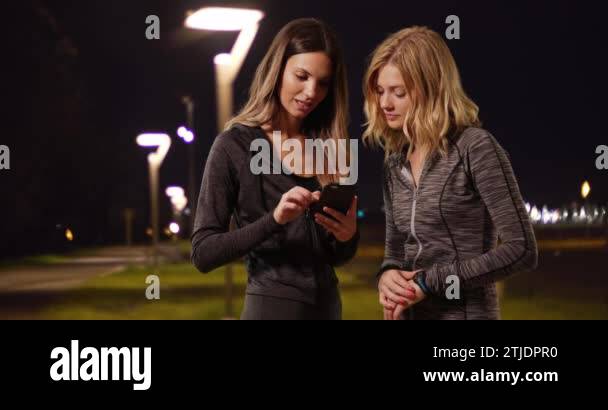 Healthy cute white girls looking at stopwatch and smart phone while out ...