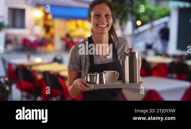 Pretty waitress at restaurant carrying tray with coffee and beverages ...