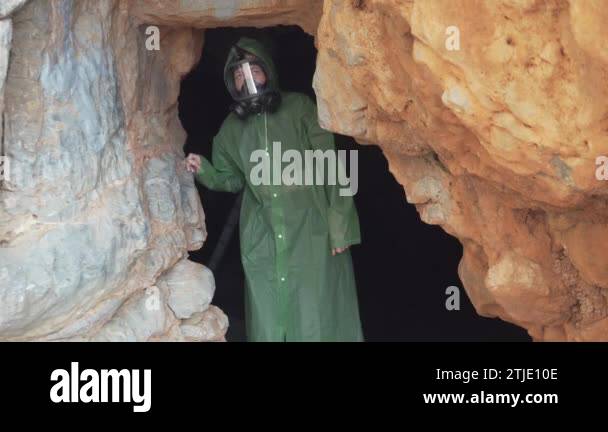 Woman wearing gas mask, coming out of a dark cave, exploring place and ...