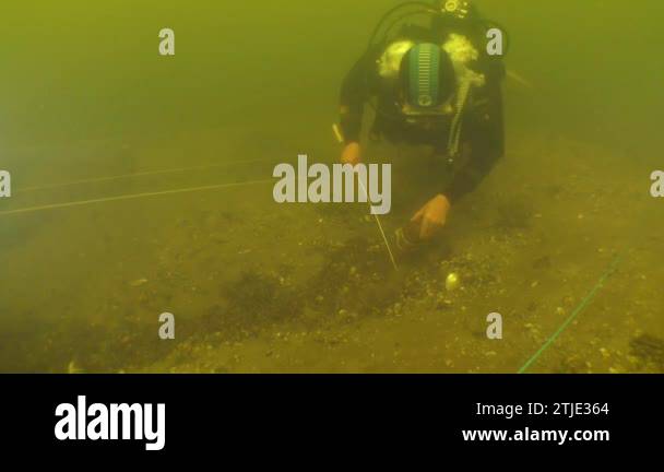 Underwater archaeological research: a scientist diver, using a metal ...