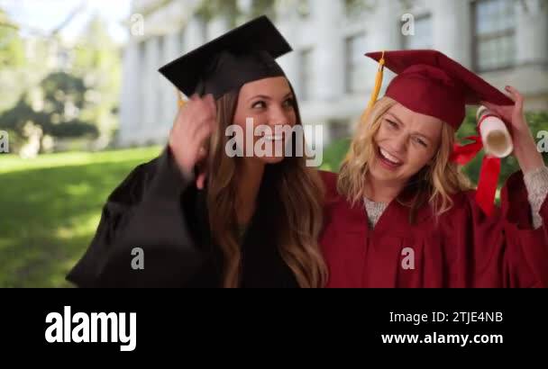 Two pretty young college graduates pose happily before their ceremony ...