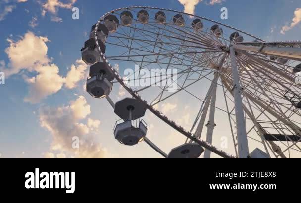 Spinning Ferris Wheel in amusement park and scenic sunset clouds in sky ...