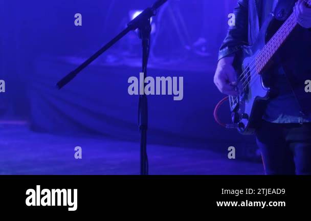Close-up of playing bass guitar during a rock concert on a big stage ...