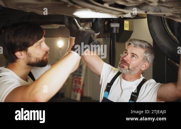Two mechanics in uniform father and son are working in auto service ...