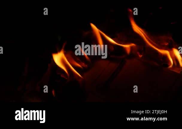 Zoomed in fire burning a substance in darkness, breeze effect on flame ...