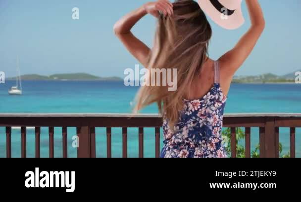 Rear view of young lady taking off fedora and letting hair flow outside ...