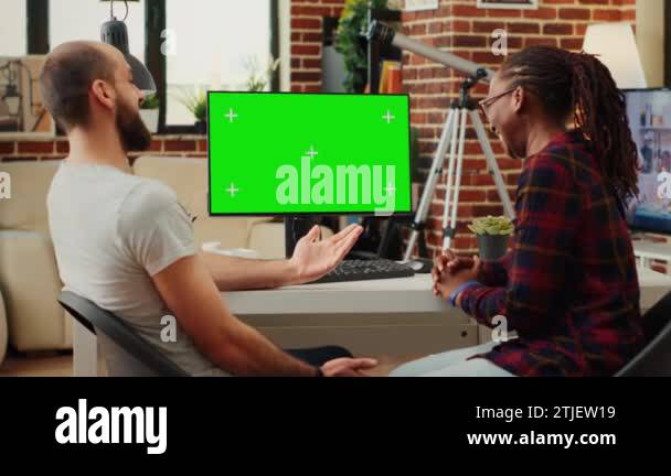Diverse team of colleagues looking at computer with greenscreen ...