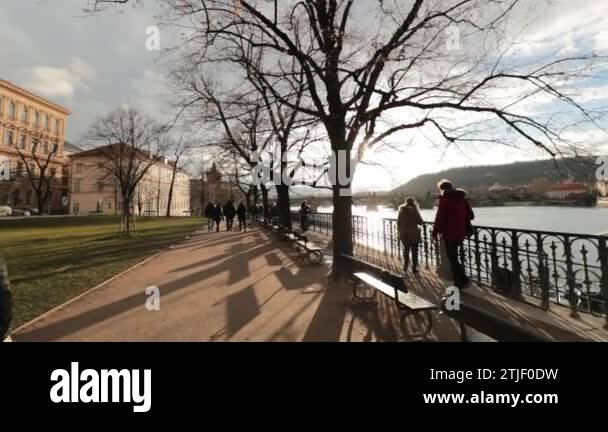 The back of group of people walking by riverside in europe during cold ...