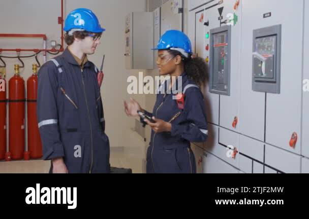 Electrical young woman and man engineer examining maintenance cabinet ...