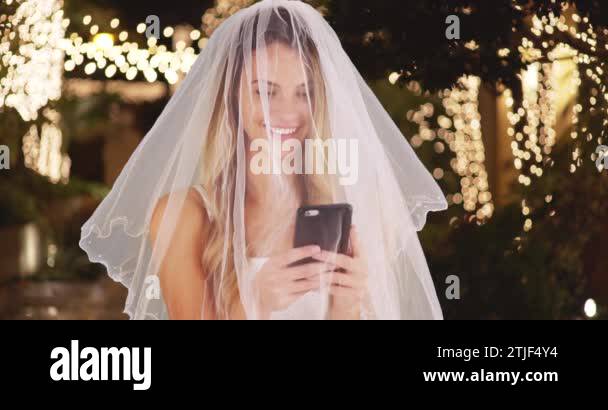 Close up of cheerful young bride in wedding dress and veil taking a ...