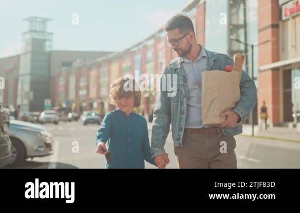 Father and son went shopping to food store. Man is holding paper bag of ...
