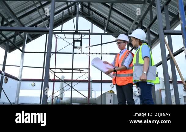 Young engineers working. Plan for construction of a warehouse. See the ...