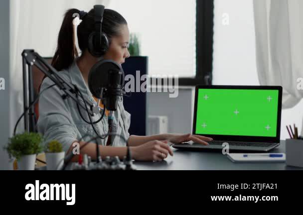 Influencer in studio presenting product on laptop with green screen background. Creative content ...