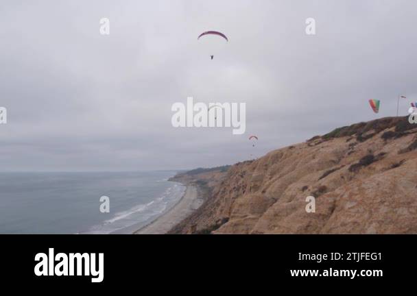 People paragliding, Torrey Pines cliff or bluff. Paraglider soaring in ...