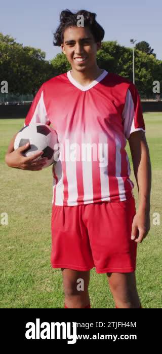 Vertical video of biracial football player with ball on field. Male ...