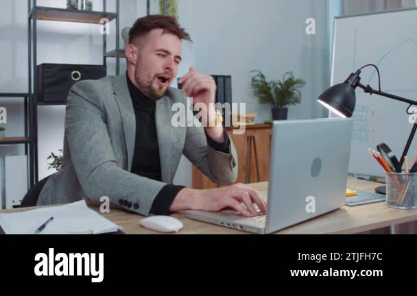Bored sleepy business man worker working on laptop computer, yawning ...