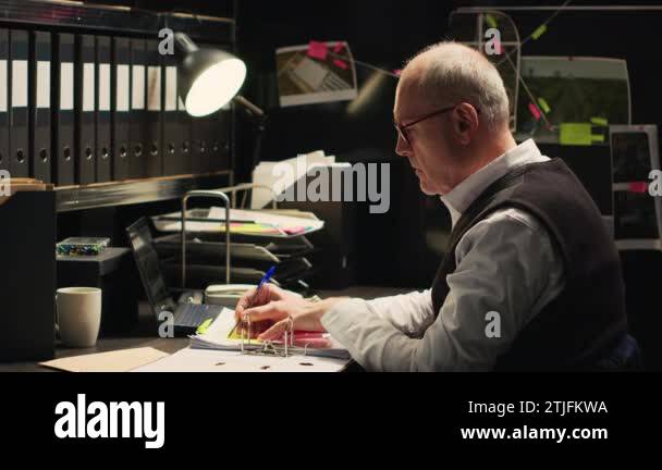 Detective gathering intelligence on files, taking notes to evaluate ...