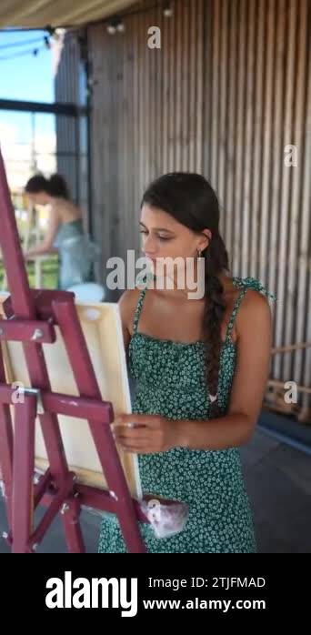 Beautiful woman artist drawing her picture on canvas with oil colors in ...