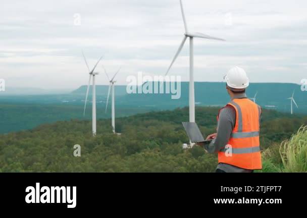 Engineer working on a wind farm atop a hill or mountain in the rural ...