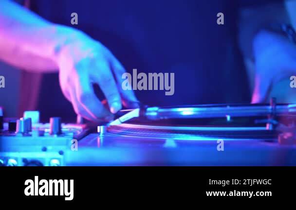 DJ mixes tracks on DJ console lit color music in nightclub party. Dj ...