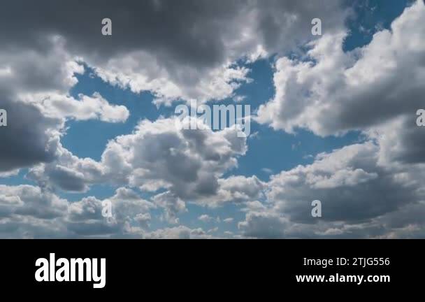 White fluffy clouds slowly float through the blue daytime sky timelapse ...