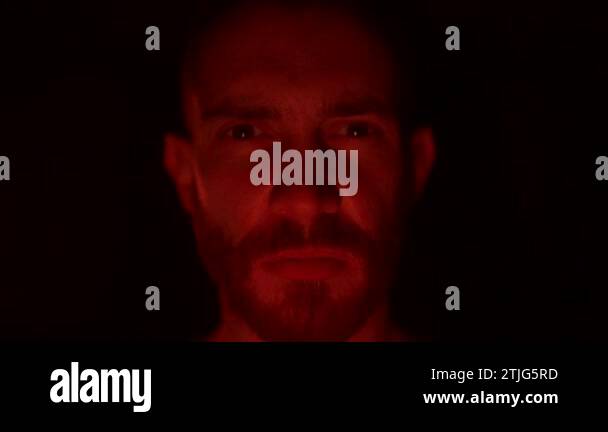 Angry man looking at camera with fury and rage, his face lit with fire ...