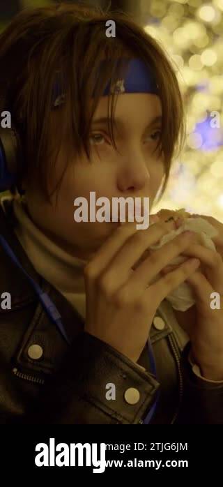 Close-up vertical footage of a teenage girl eating cheeseburger on the ...