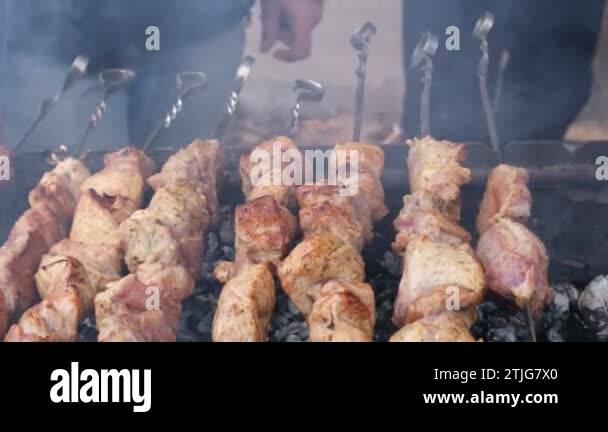 a man roasts meat on a fire. Onion and barbecue. Grilling pork neck ...