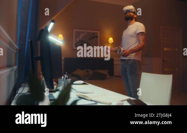Man works remotely at home using VR headset and wireless controllers ...