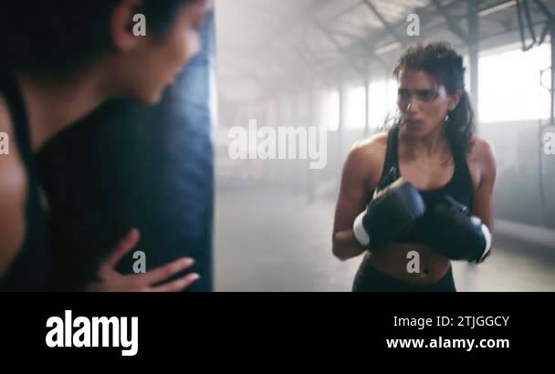 Boxing, personal trainer and coaching with woman in gym for martial arts, workout and strong ...