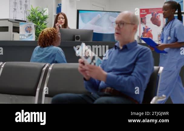 Asian receptionist working at hospital reception counter, using ...