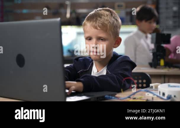 Portrait of smart cute little boy programming software for robotics ...