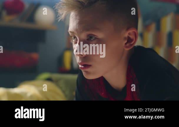 Unhappy teenage boy sits in his room alone. Frustrated schoolboy thinks ...