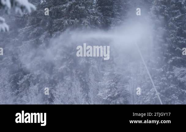 Snow cannon in a snow dust. Snowmaking is the production of snow by ...