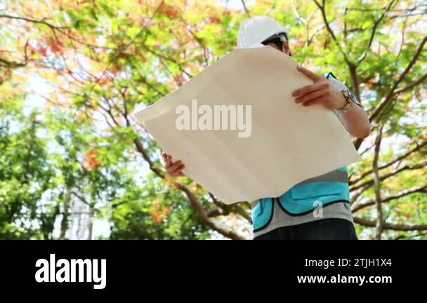Masked asian architect looks at the floor plan and observes the area ...