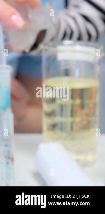 Young woman mixing liquids in test tube with multiethnic children ...