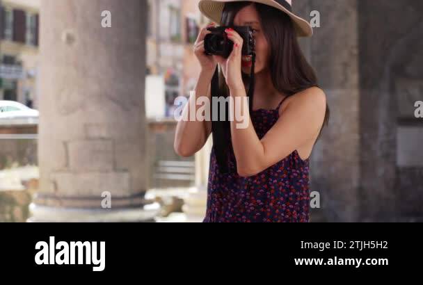 Happy young female tourist in her 20s taking photos with dslr camera in ...