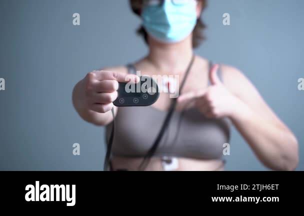 Unrecognizable woman in medical mask wears holter monitor for daily ...