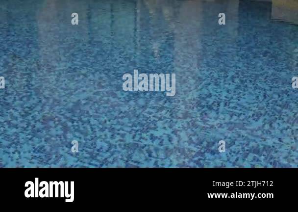 Rain droplets drops falling onto the surface of a swimming pool, Close ...