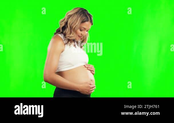 Stomach, pregnant and a happy woman on a green screen with a smile ...