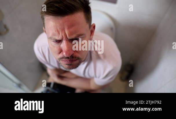 Sad man sits on toilet with bowel problems and smiles closeup. Constipation hemorrhoids diarrhea ...