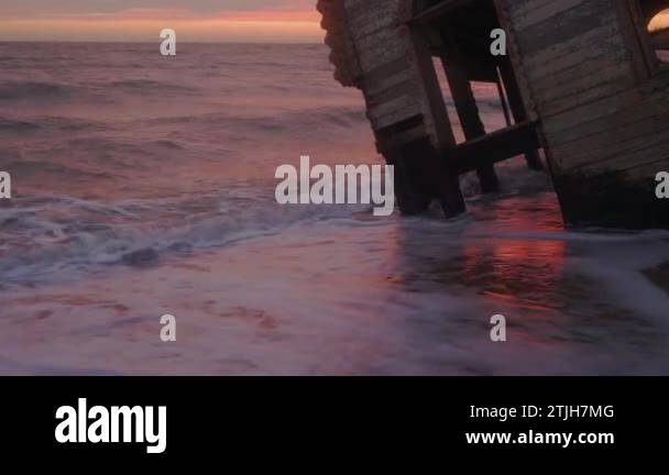 Mysterious vintage flooded leaning wooden house washed by sea waves, at ...