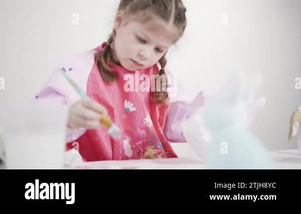 Little girl painting paper mache figurine at homeschooling art class ...