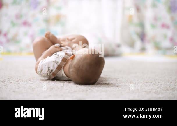 Happy healthy six-month-old baby trying roll over from the back to the ...