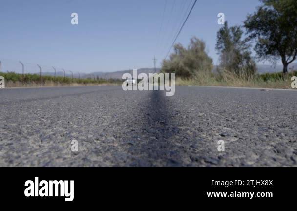 A low angle of 2 different cars driving by on a hot road in Napa Ca ...