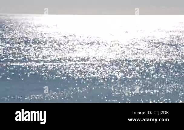 Abstract blurred background.Spots of white reflections of shining sun on blue surface of sea ...